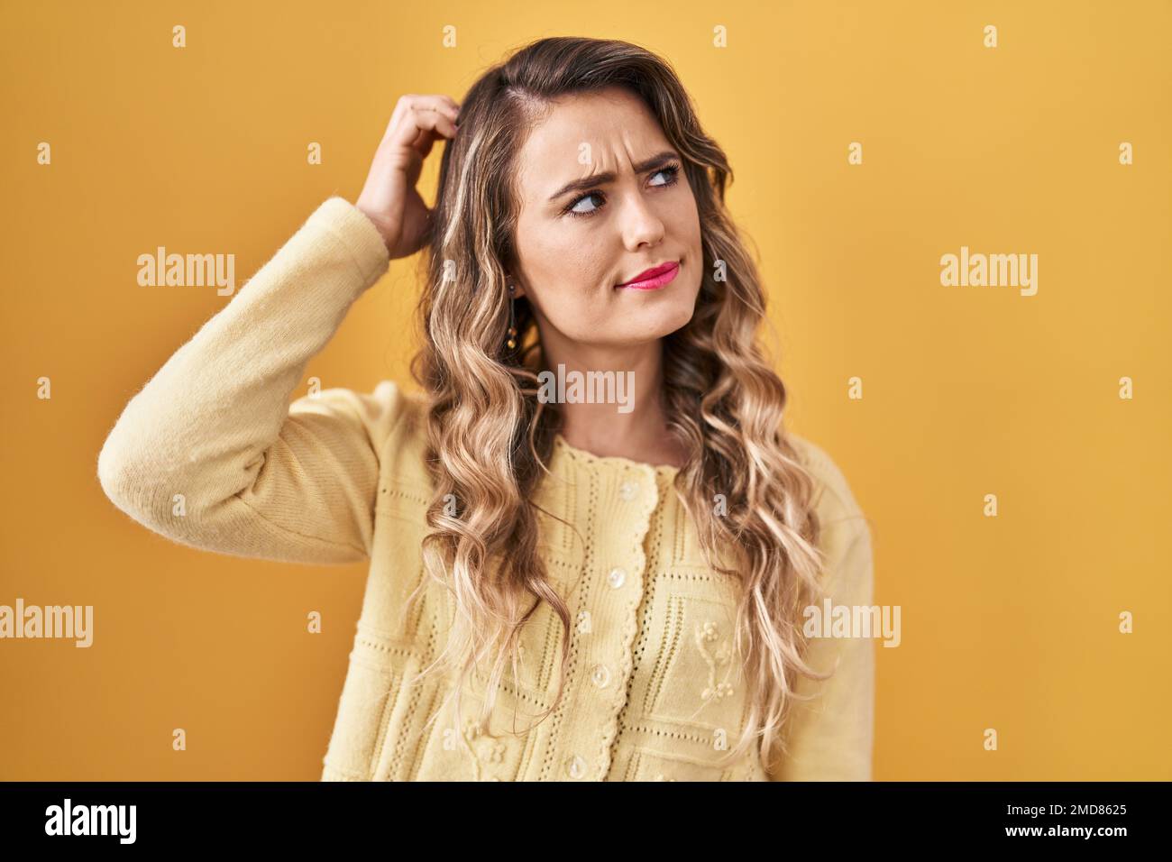 Young caucasian woman standing over yellow background confuse and ...