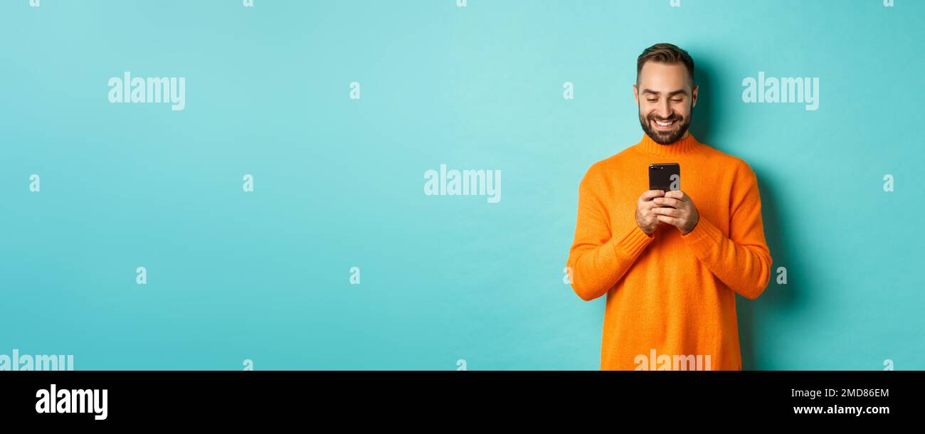 Handsome man smiling and texting message on mobile phone, communicating ...