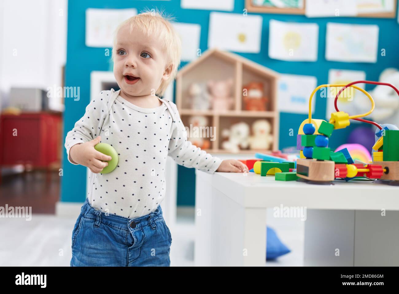 Adorable blond toddler playing with toys standing at kindergarten Stock ...