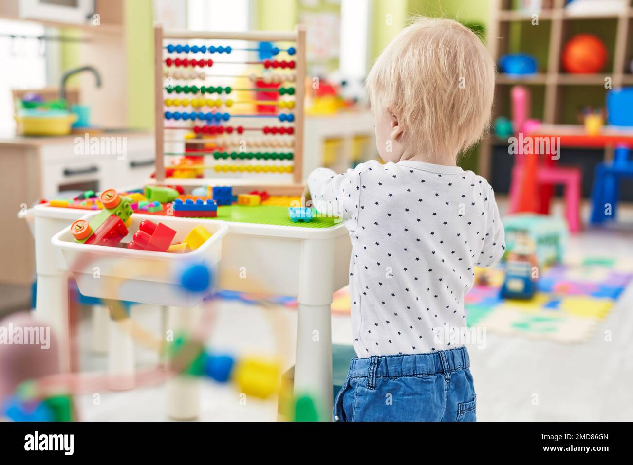 Adorable blond toddler playing with construction blocks standing at ...