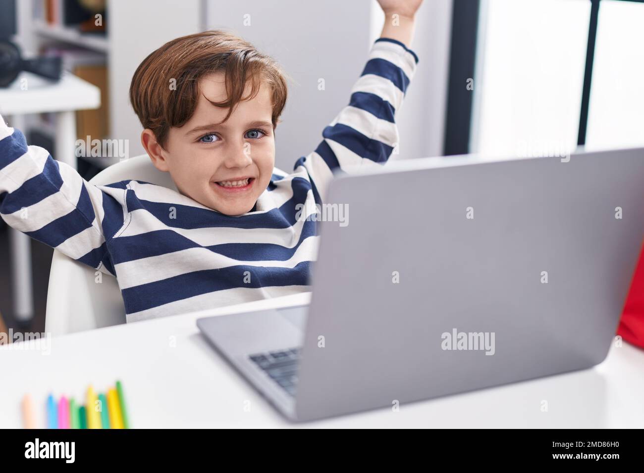 Adorable hispanic boy student using laptop with cheerful expression at ...