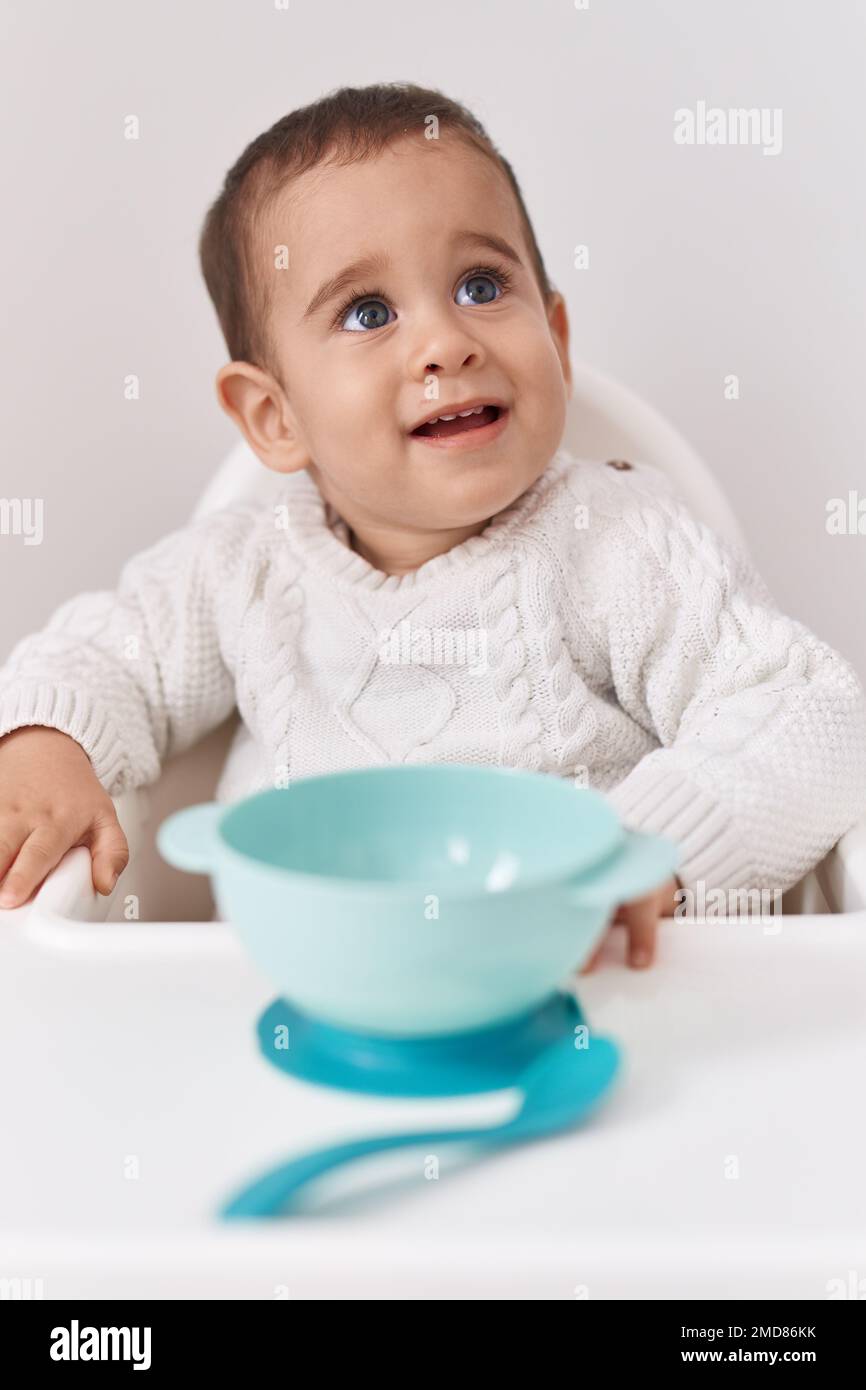 Adorable hispanic toddler smiling confident sitting on highchair over ...