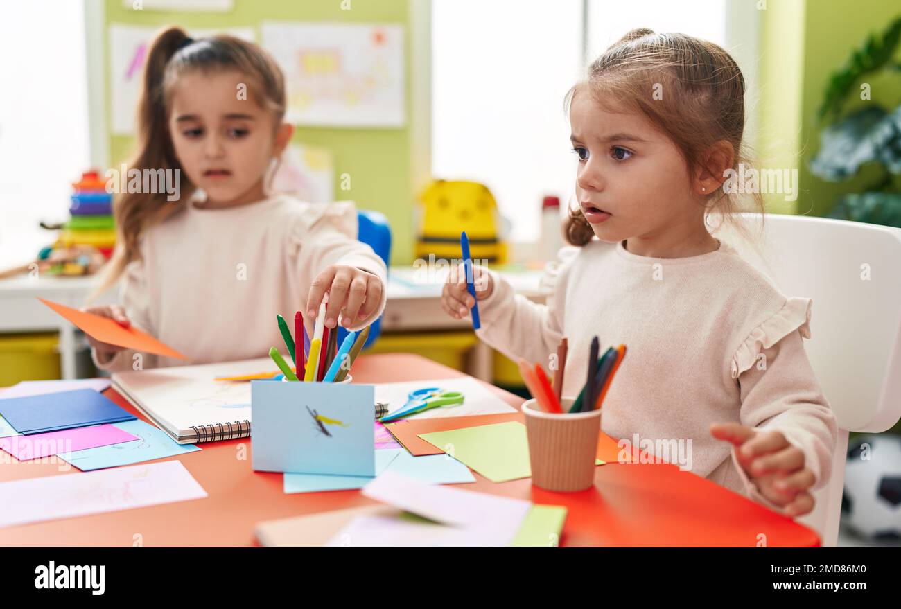 Two kids preschool students sitting on table drawing on paper at ...
