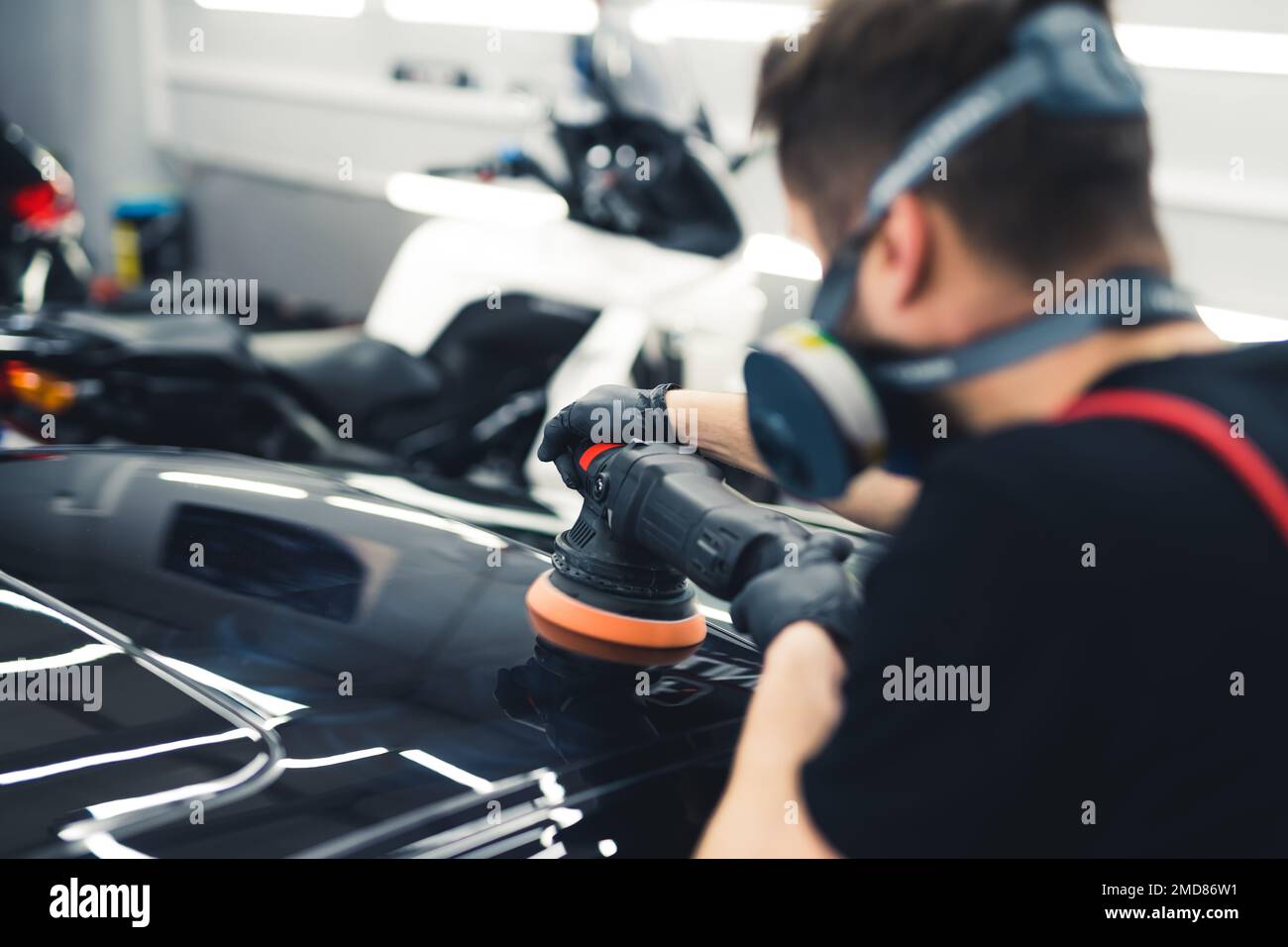 Professional car detailer polishing black car paintwork with orbital ...