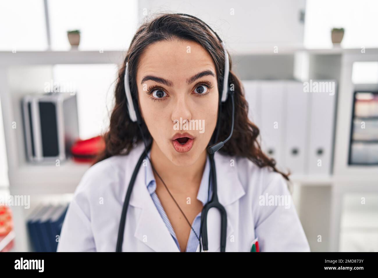 Young doctor woman working on online appointment scared and amazed with ...