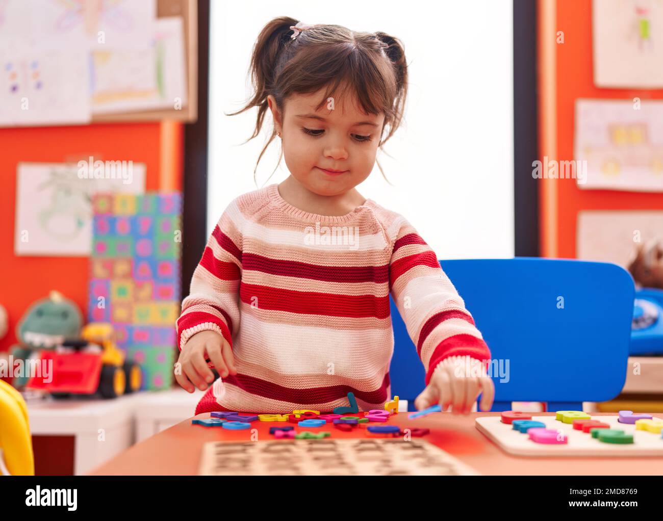 Adorable hispanic girl playing with maths puzzle game standing at ...