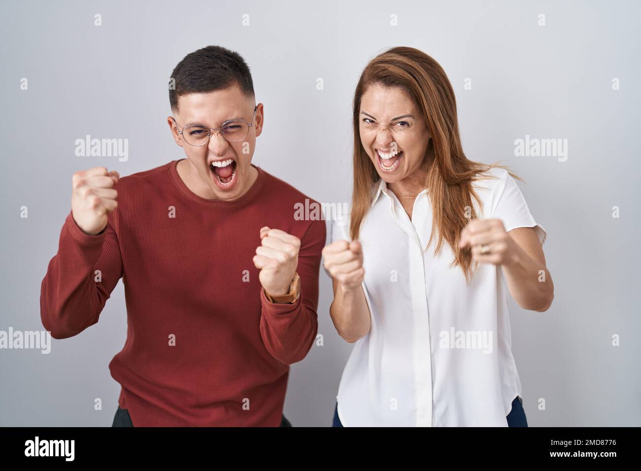 Mother and son standing together over isolated background angry and mad ...