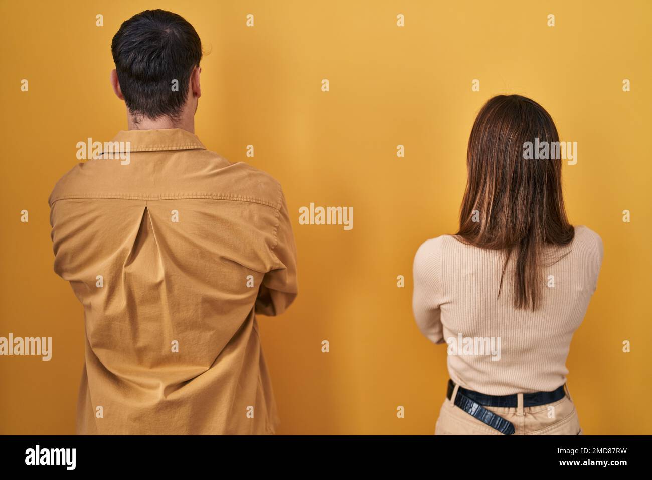 Young hispanic couple standing over yellow background standing ...