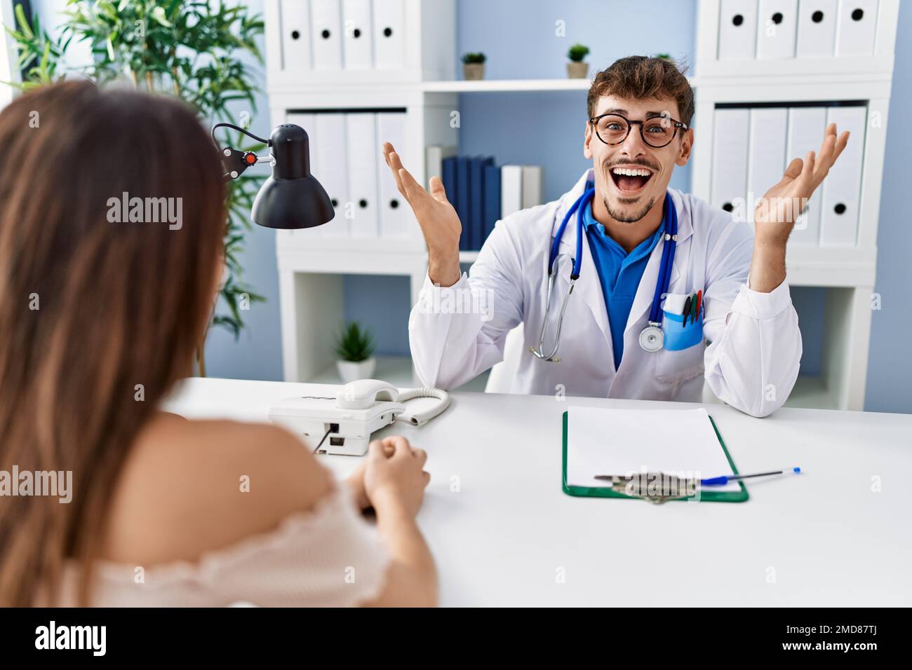Young doctor with client at medical clinic celebrating crazy and amazed ...
