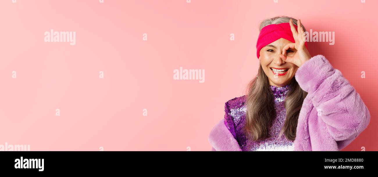 Fashion. Close-up of fashionable asian senior woman smiling, showing OK ...