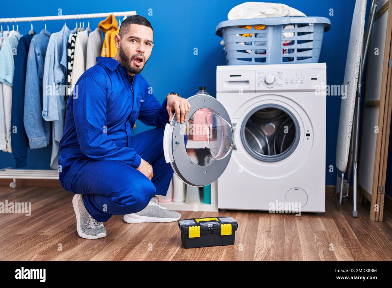 Hispanic repairman working on washing machine scared and amazed with ...