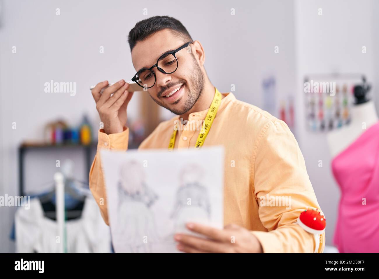 Young hispanic man tailor listening voice message by smartphone looking ...