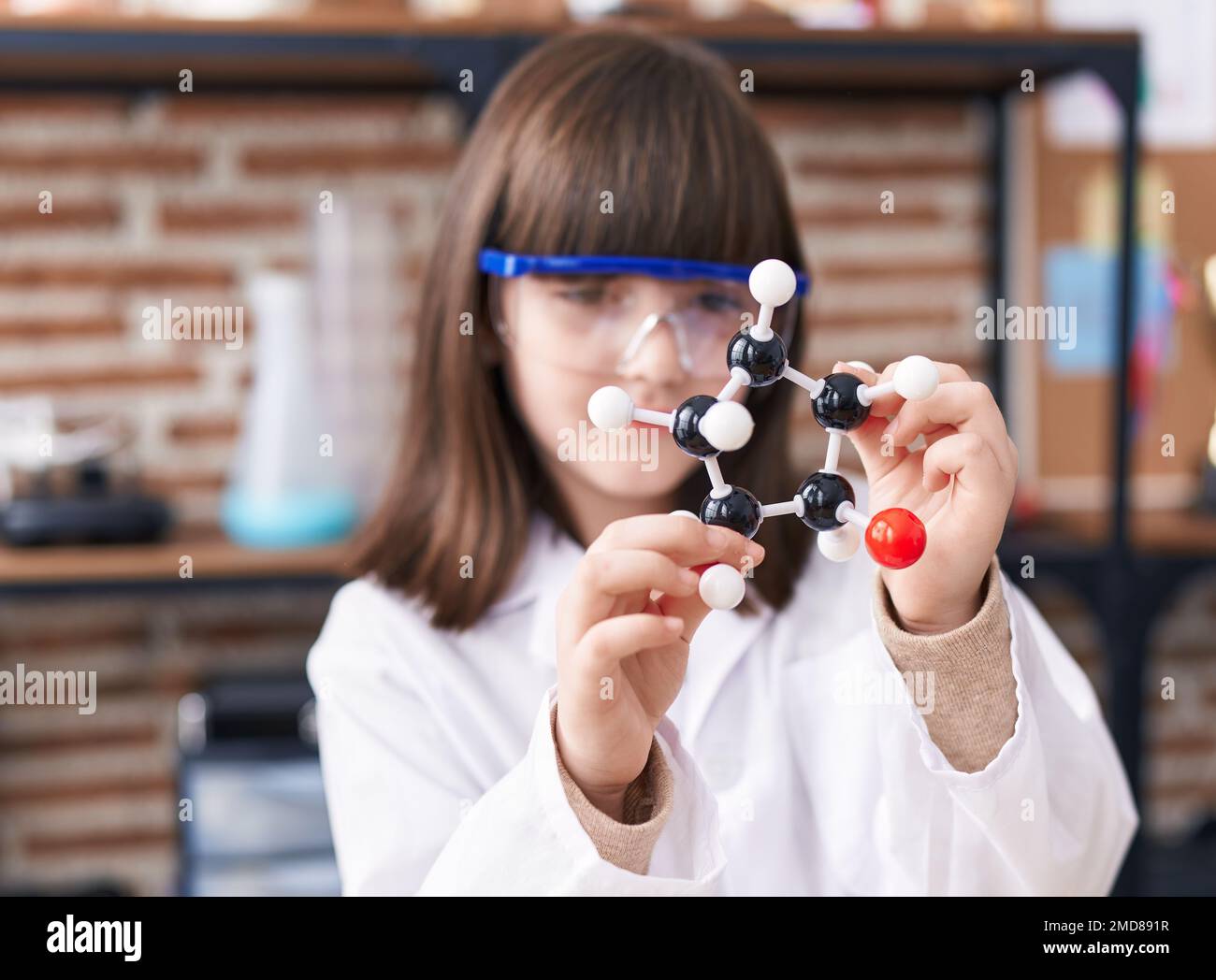 Adorable hispanic girl student holding molecules at laboratory ...