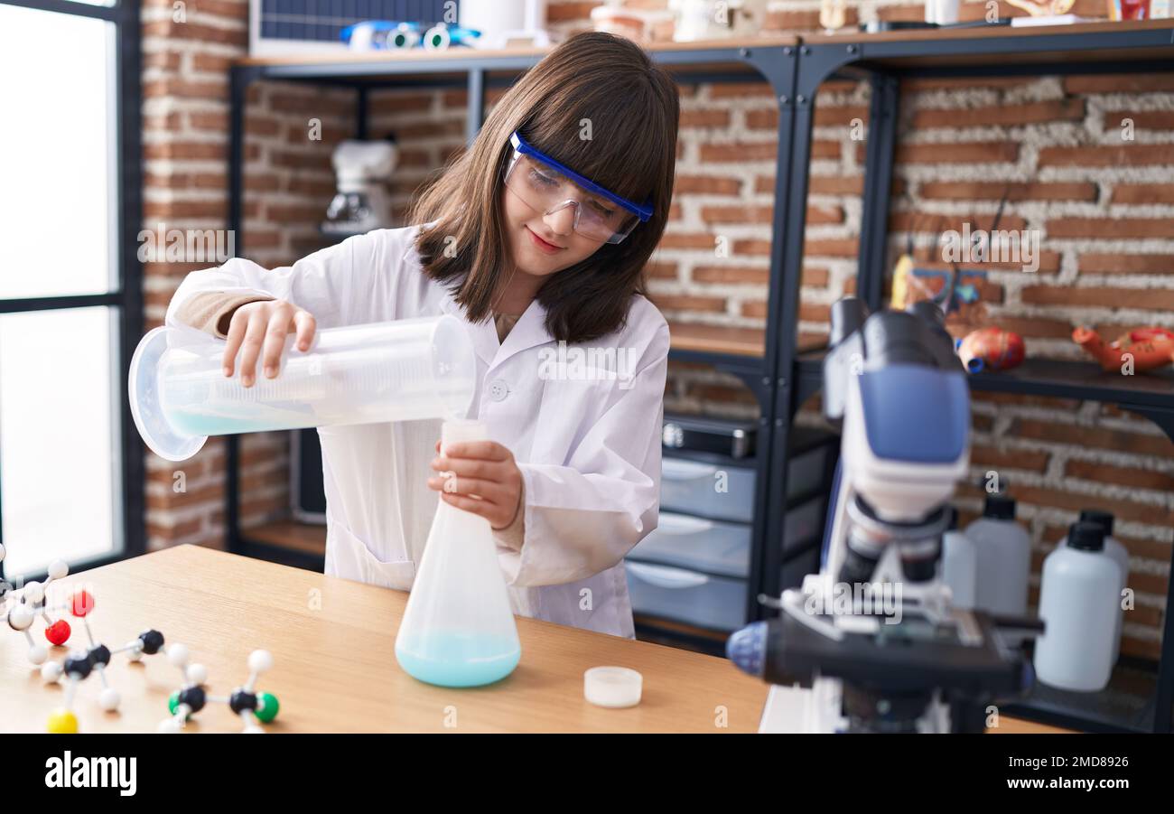 Adorable hispanic girl student pouring liquid on test tube at ...