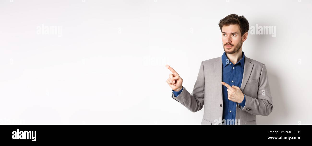 Handsome businessman in suit pointing, looking left at logo with ...