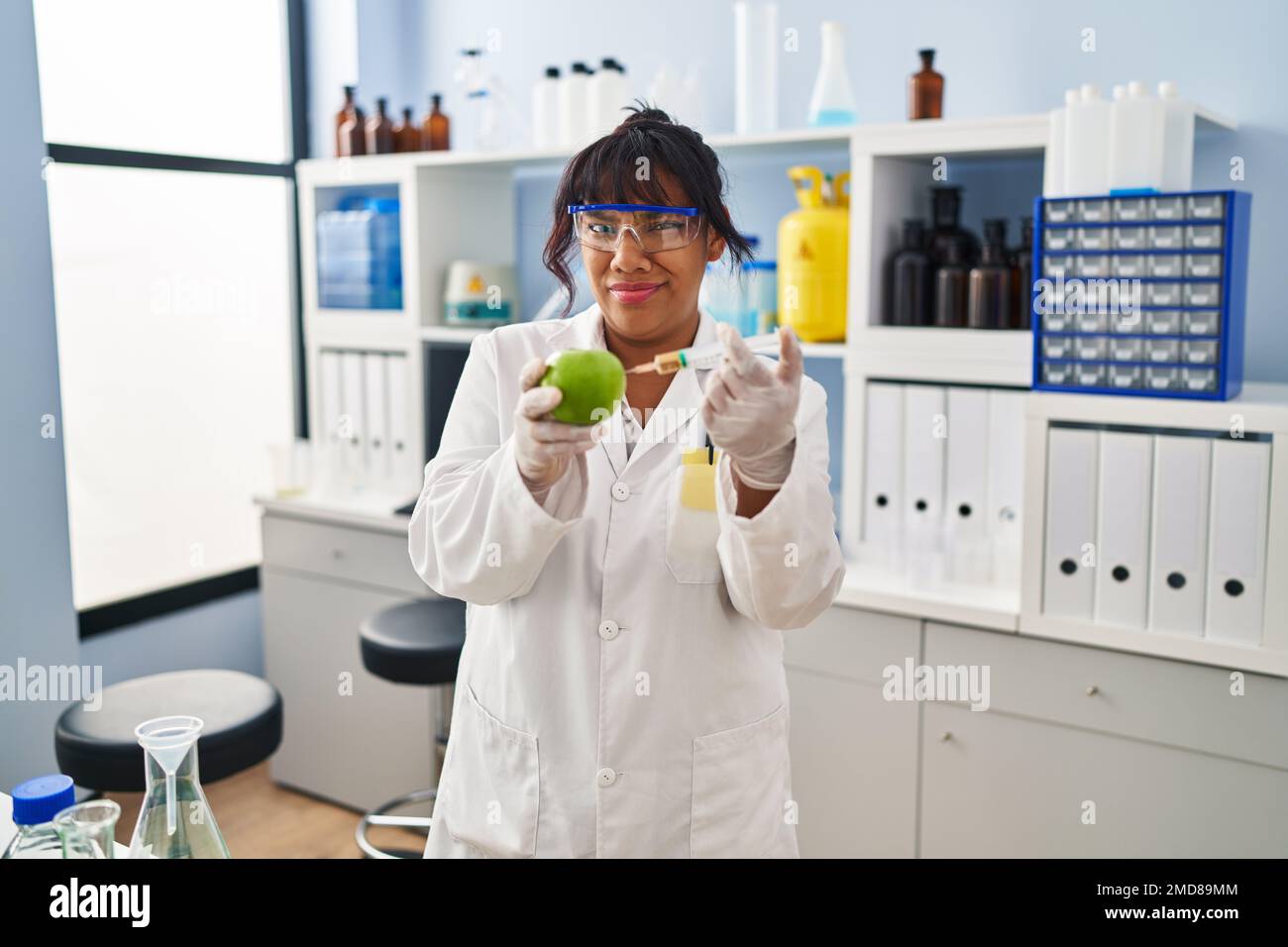 Hispanic woman working at scientist laboratory with apple clueless and ...