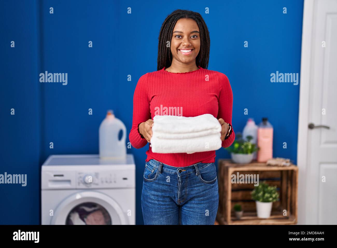 Young african american with braids holding clean laundry smiling with a ...