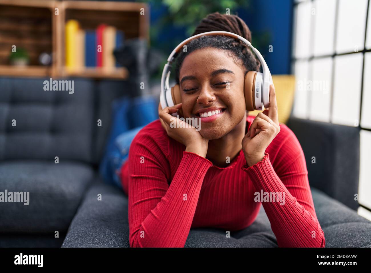 African american woman listening to music lying on sofa at home Stock ...