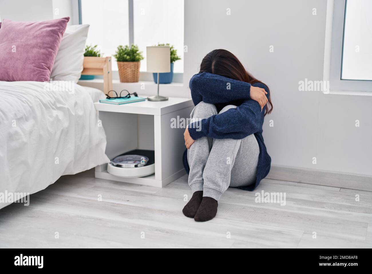 Young hispanic woman sitting on floor crying at bedroom Stock Photo - Alamy
