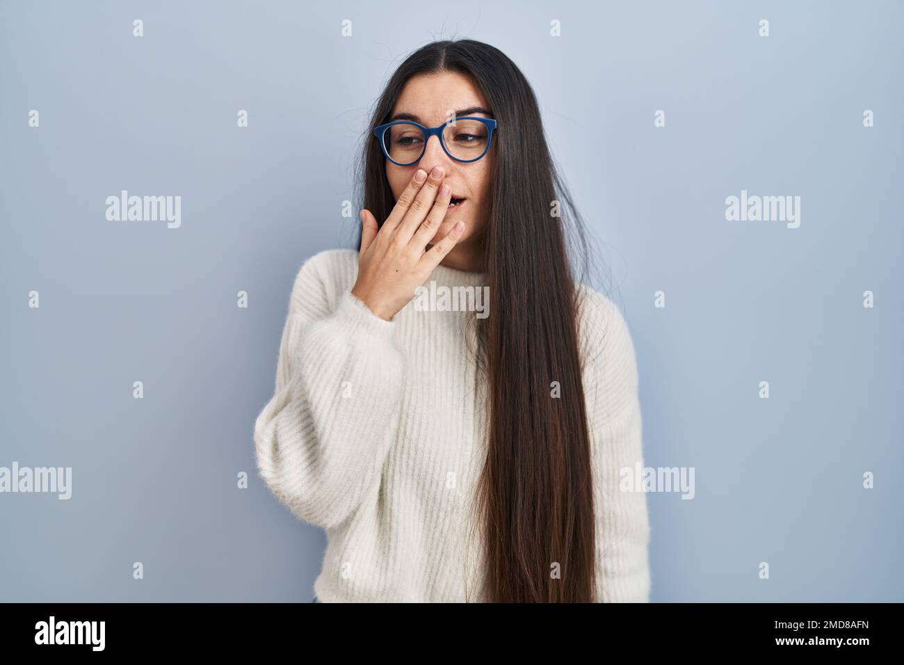 Young hispanic woman wearing casual sweater over blue background bored ...