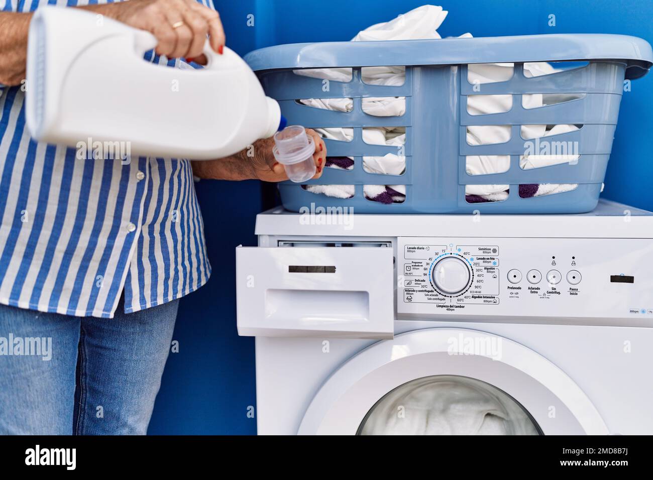 Senior grey-haired woman smiling confident pouring detergent on washing ...