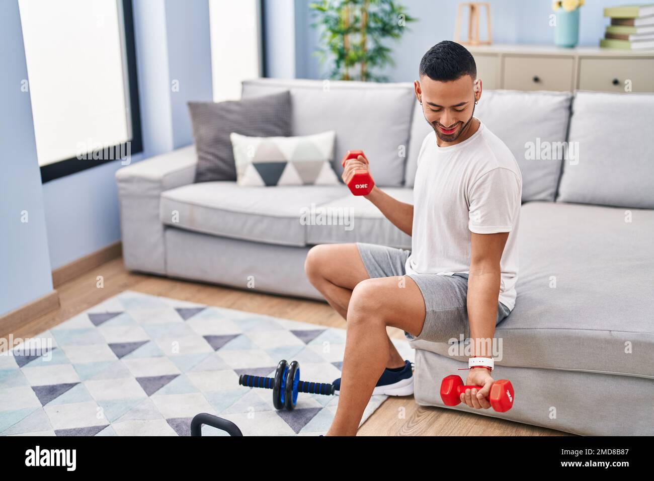 African american man smiling confident using dumbbells training at home ...