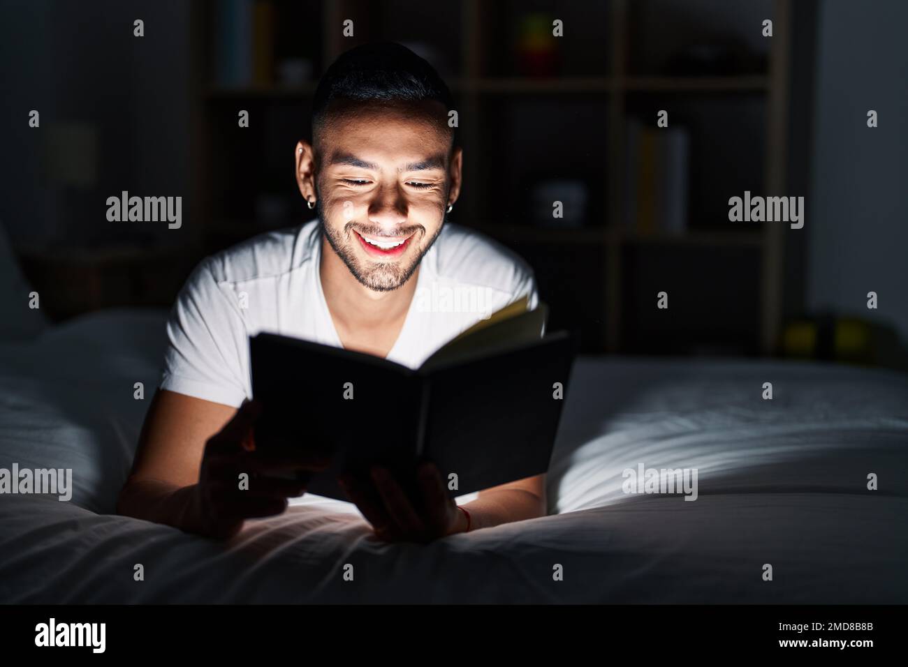 African american man reading book lying on bed at bedroom Stock Photo ...