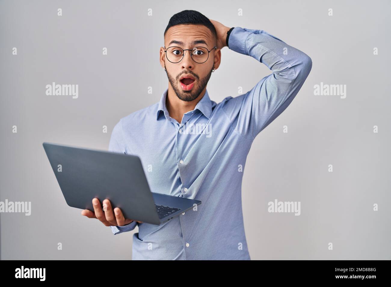 Young hispanic man working using computer laptop crazy and scared with ...