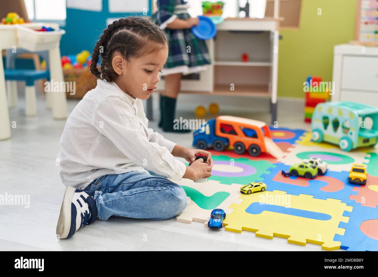 Adorable hispanic boy playing with cars toy sitting on floor at ...