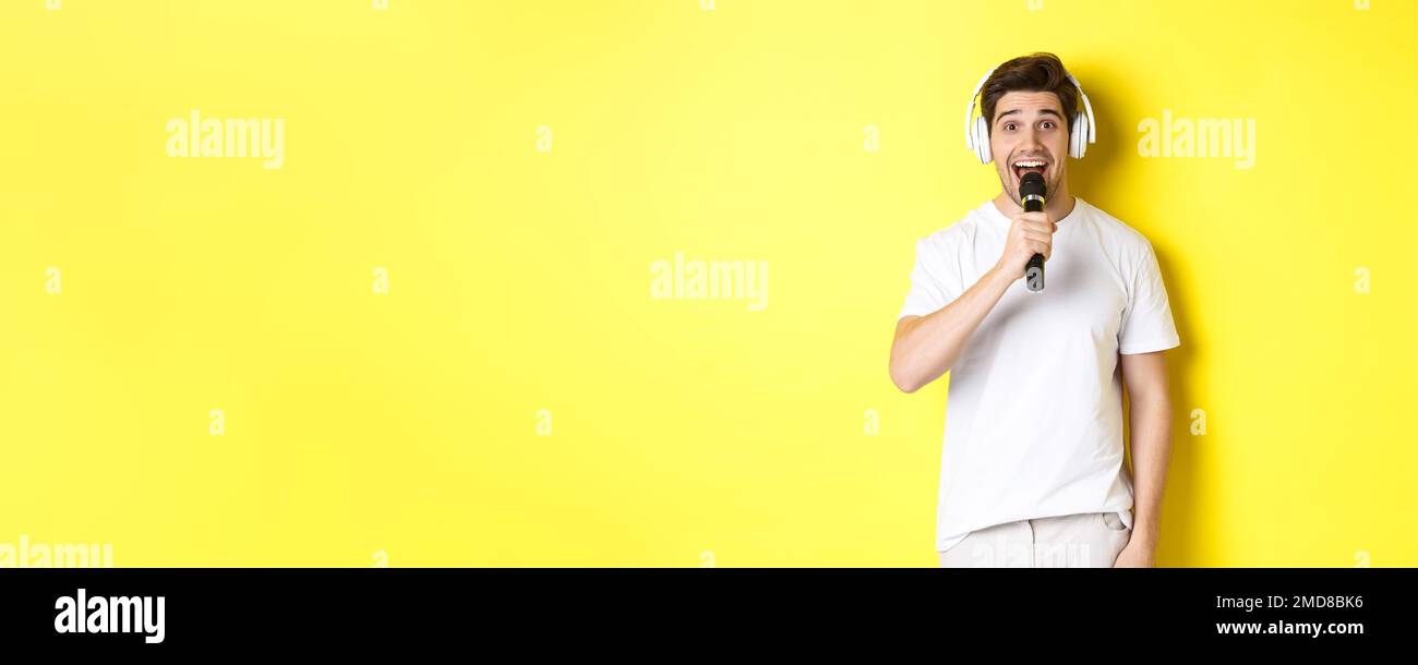 Man in headphones holding microphone, singing karaoke song, standing ...