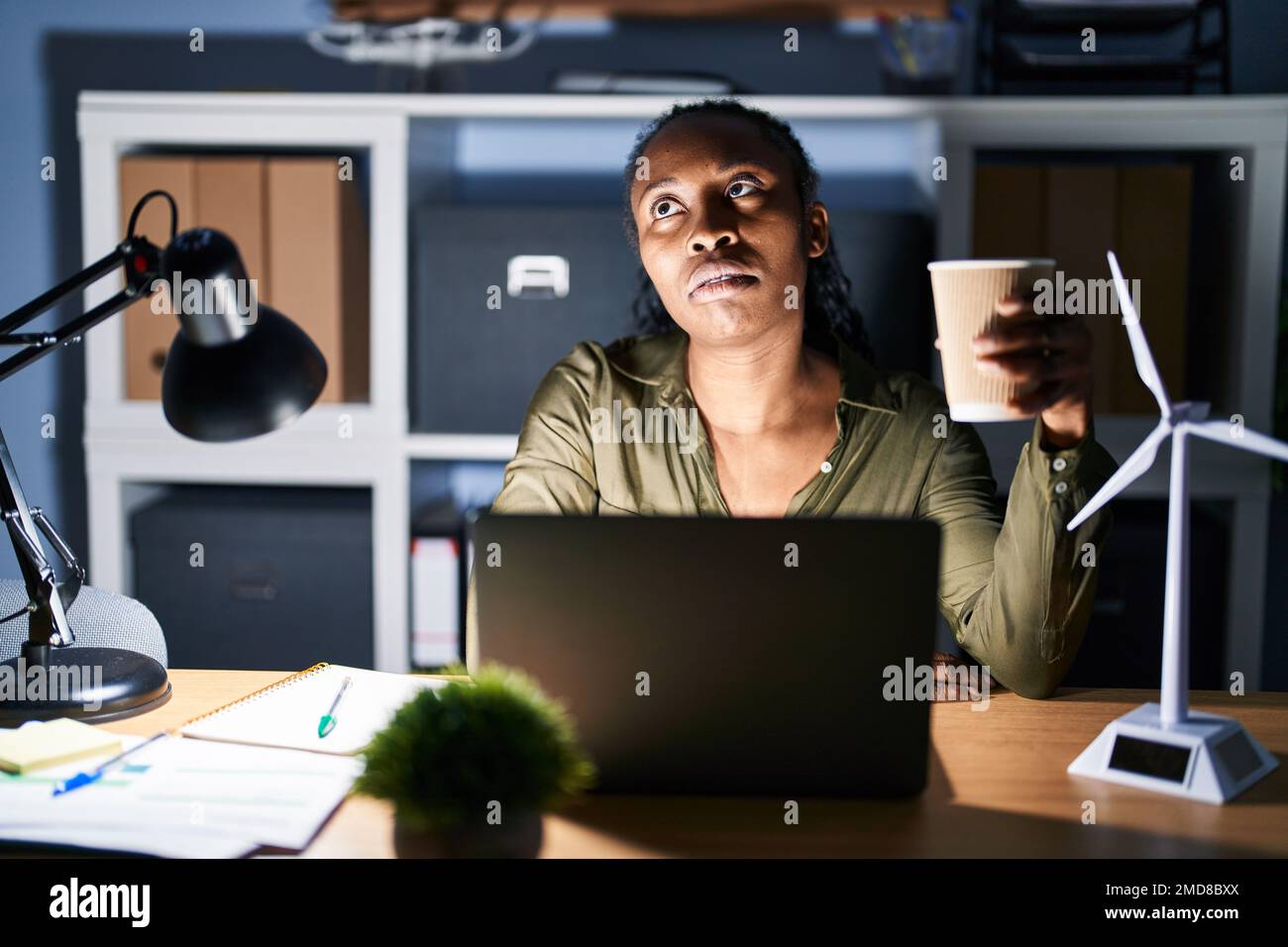African woman working using computer laptop at night looking sleepy and ...