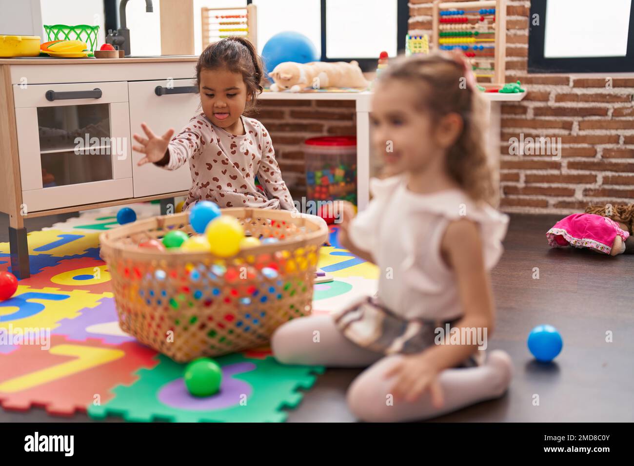 Two kids playing with balls sitting on floor at kindergarten Stock ...