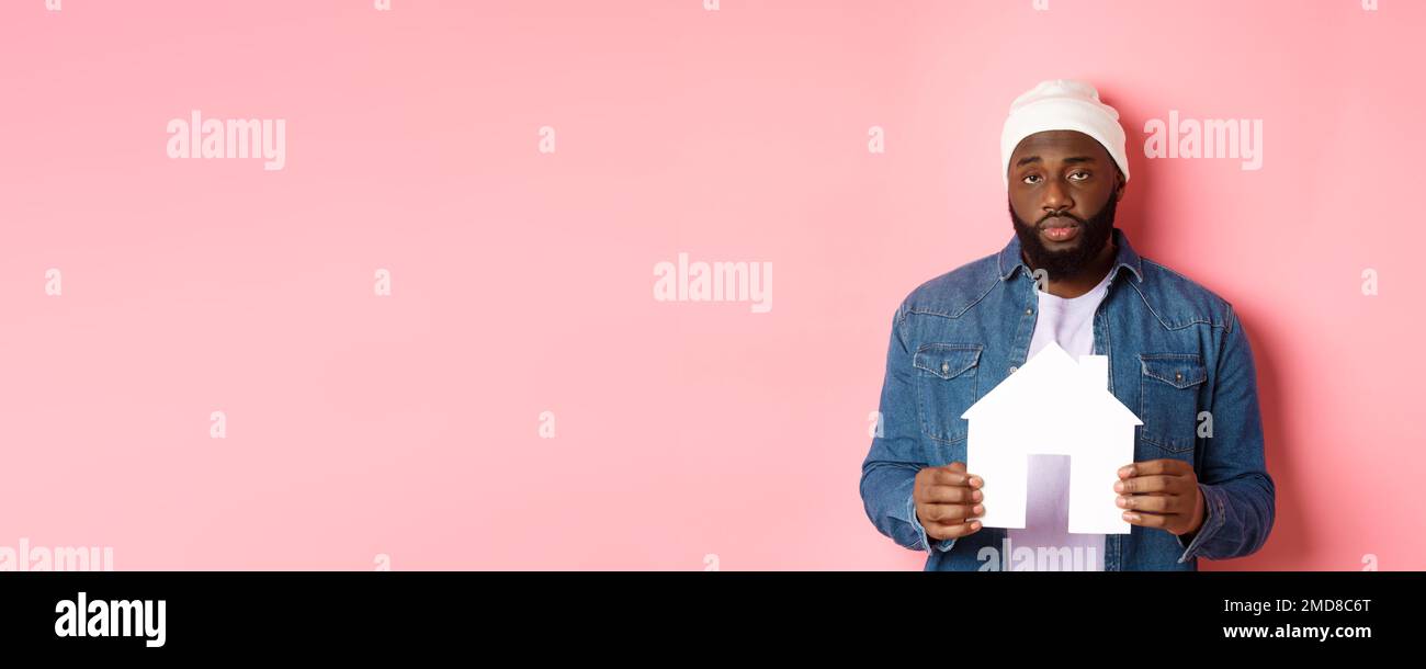 Real estate concept. Sad and tired Black man staring unamused at camera ...