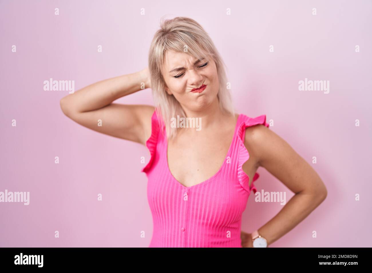 Young caucasian woman standing over pink background suffering of neck ...