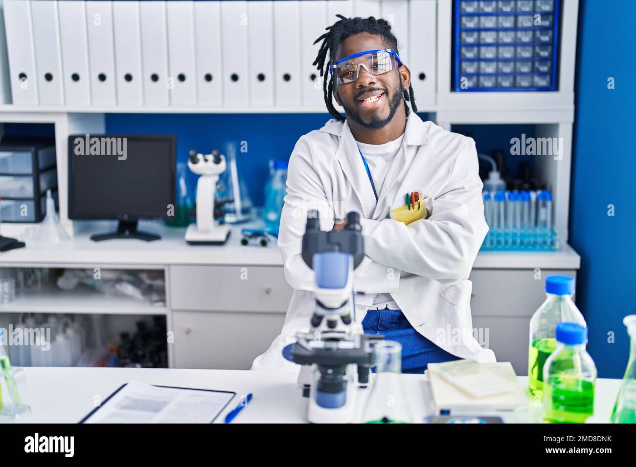 African man with dreadlocks working at scientist laboratory happy face smiling with crossed arms ...