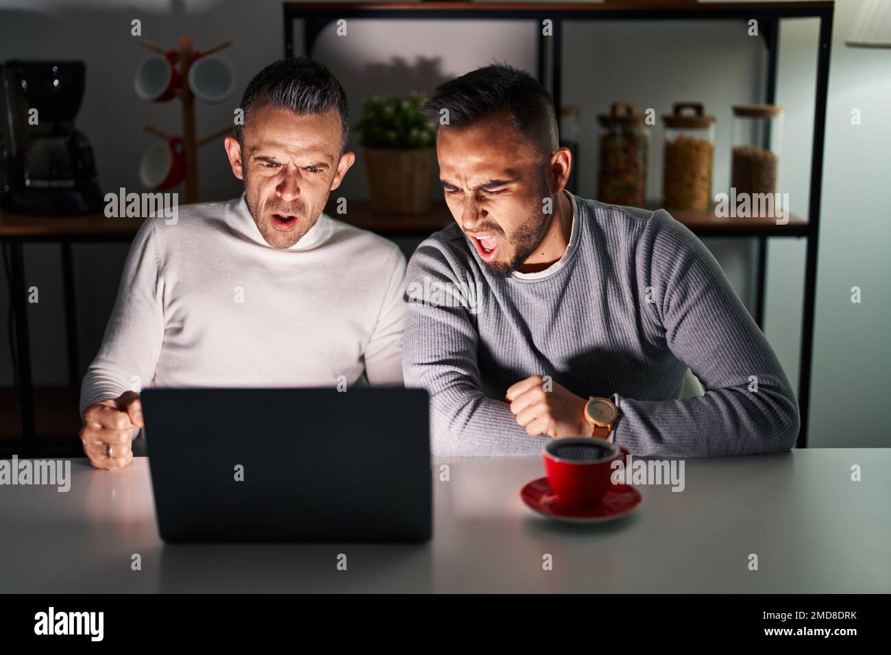 Homosexual couple using computer laptop angry and mad screaming ...