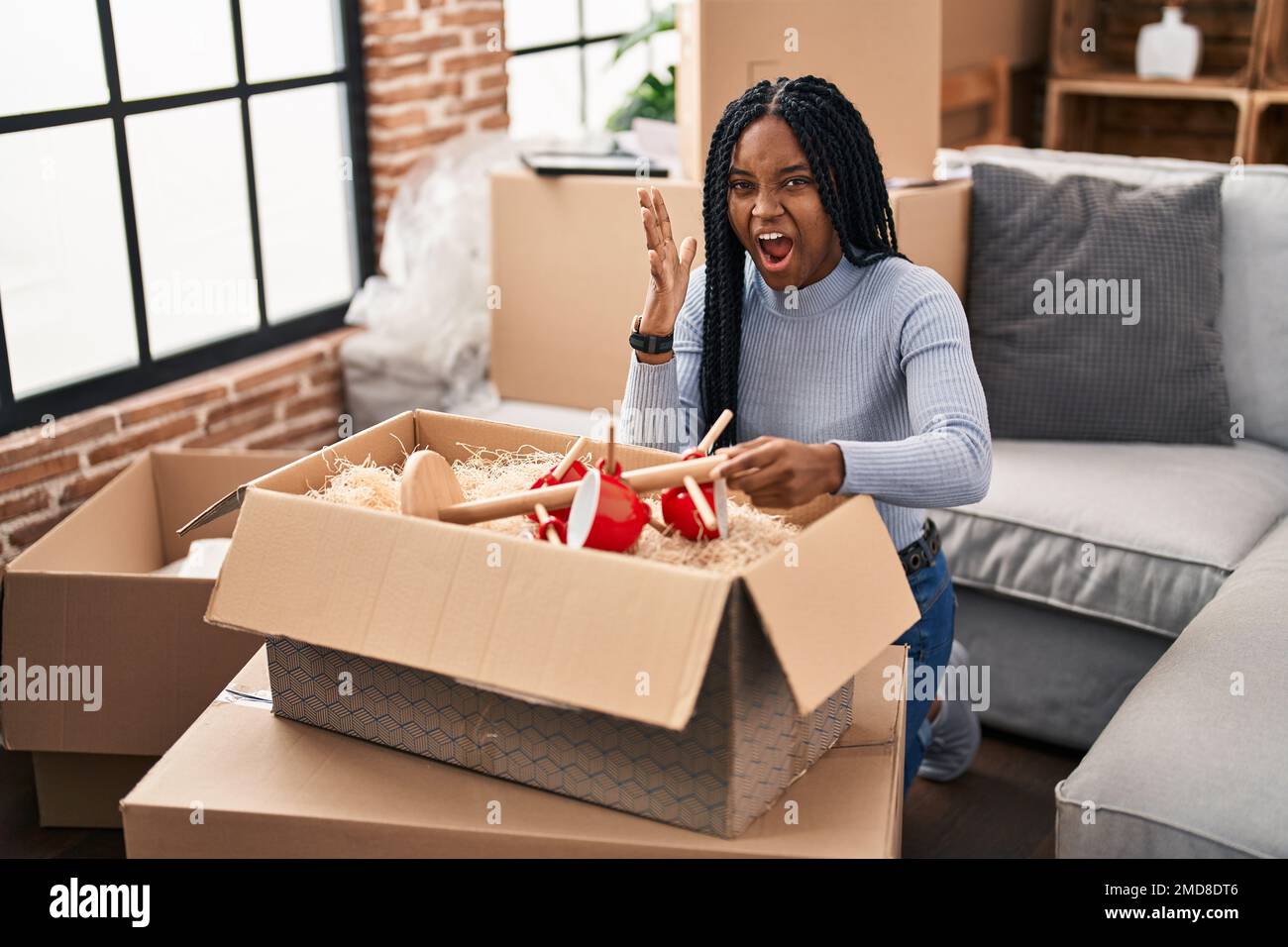African american woman moving to a new home opening boxes celebrating ...