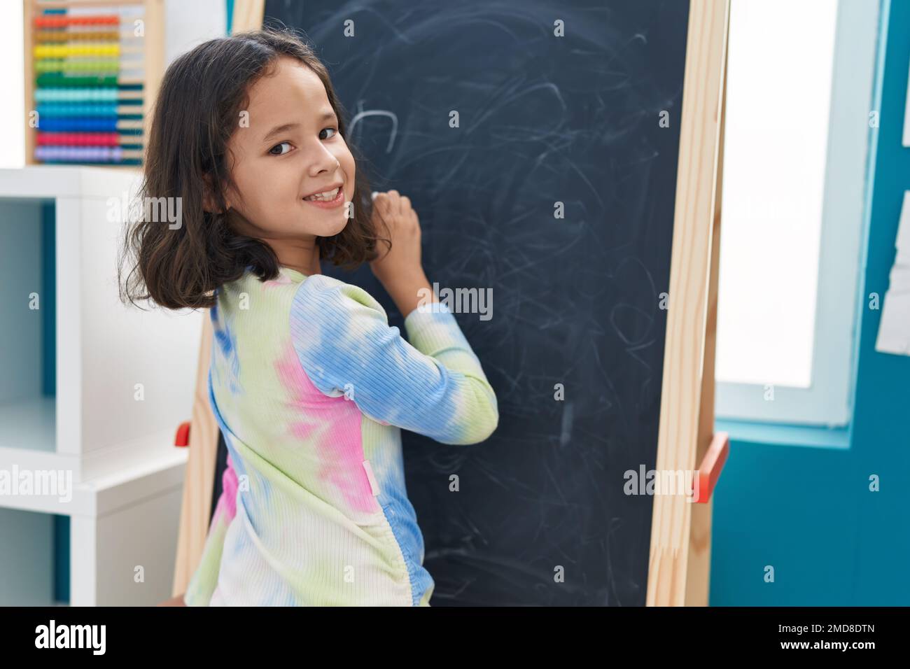 Adorable chinese girl student smiling confident drawing on blackboard ...