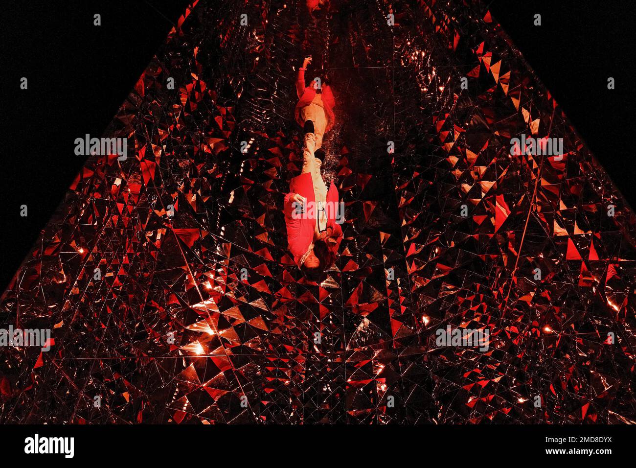 A woman takes a selfie inside a mirror box illuminated with lights at ...