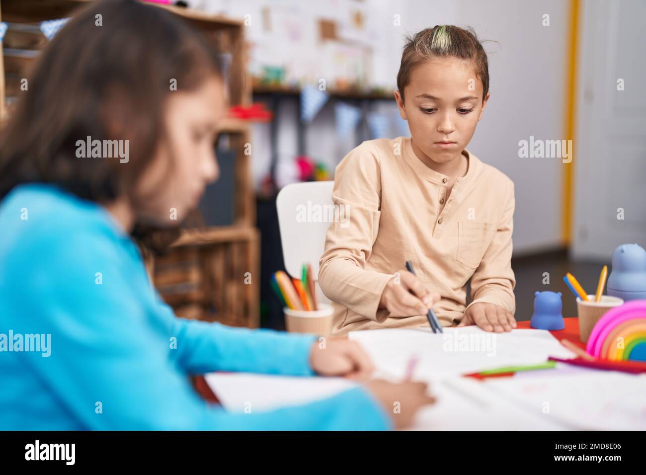 Two kids students sitting on table drawing on paper at kindergarten ...