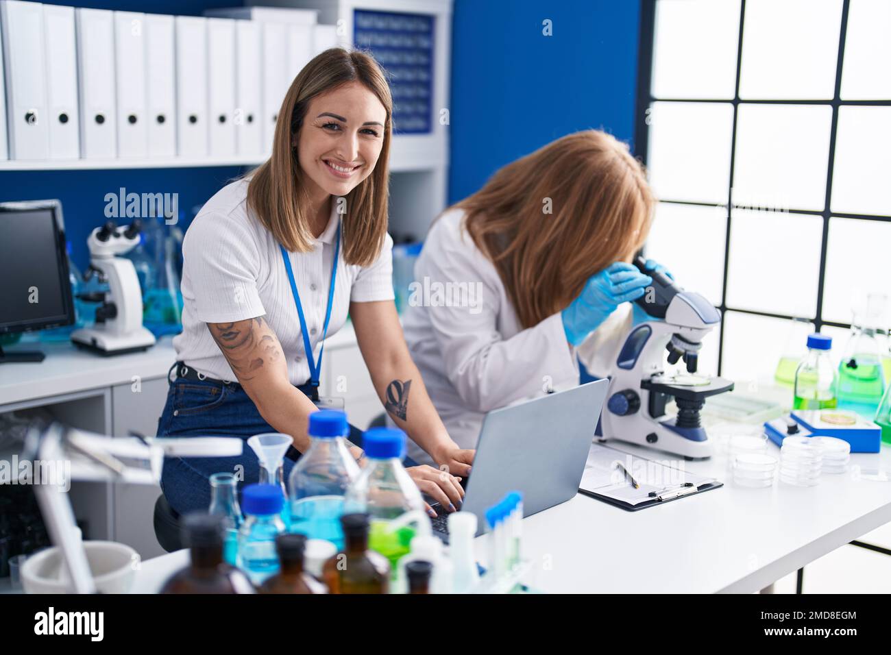 Mother and daughter scientists using laptop and microscope at laboratory Stock Photo - Alamy