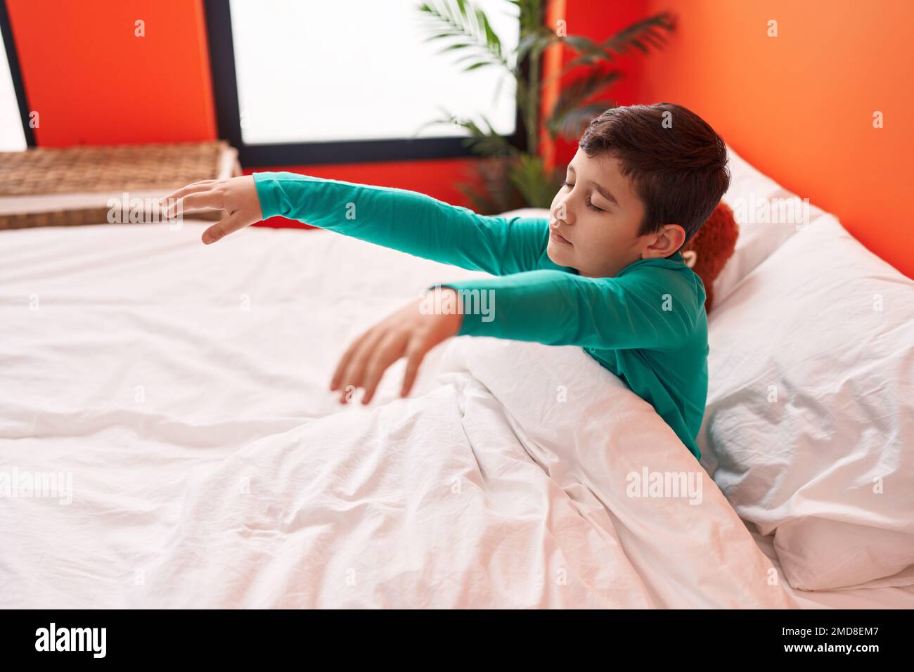 Adorable hispanic boy somnambulist sitting on bed at bedroom Stock ...