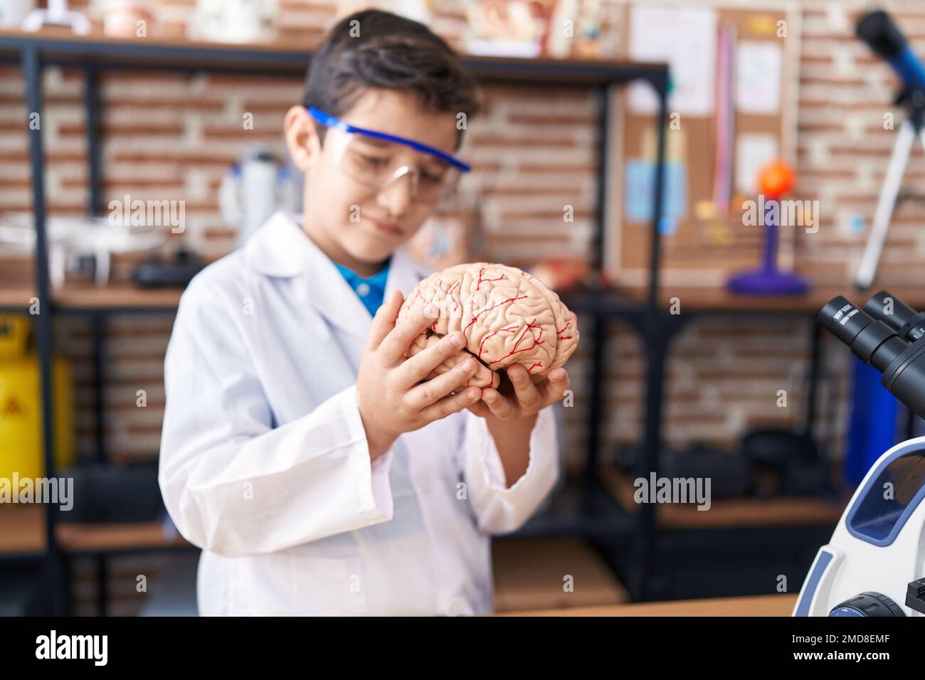 Adorable hispanic boy student smiling confident holding brain at ...