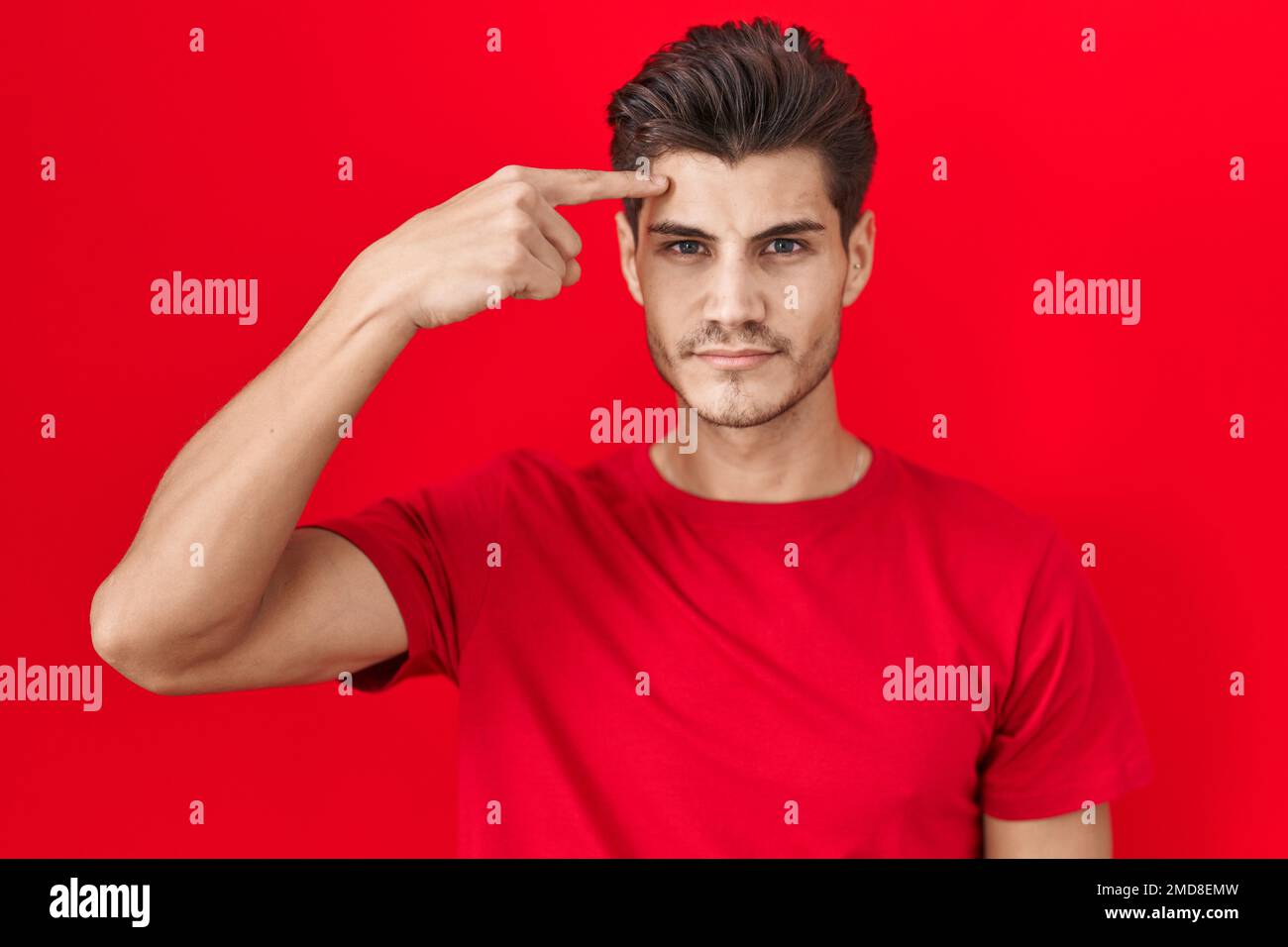 Young hispanic man standing over red background pointing unhappy to ...