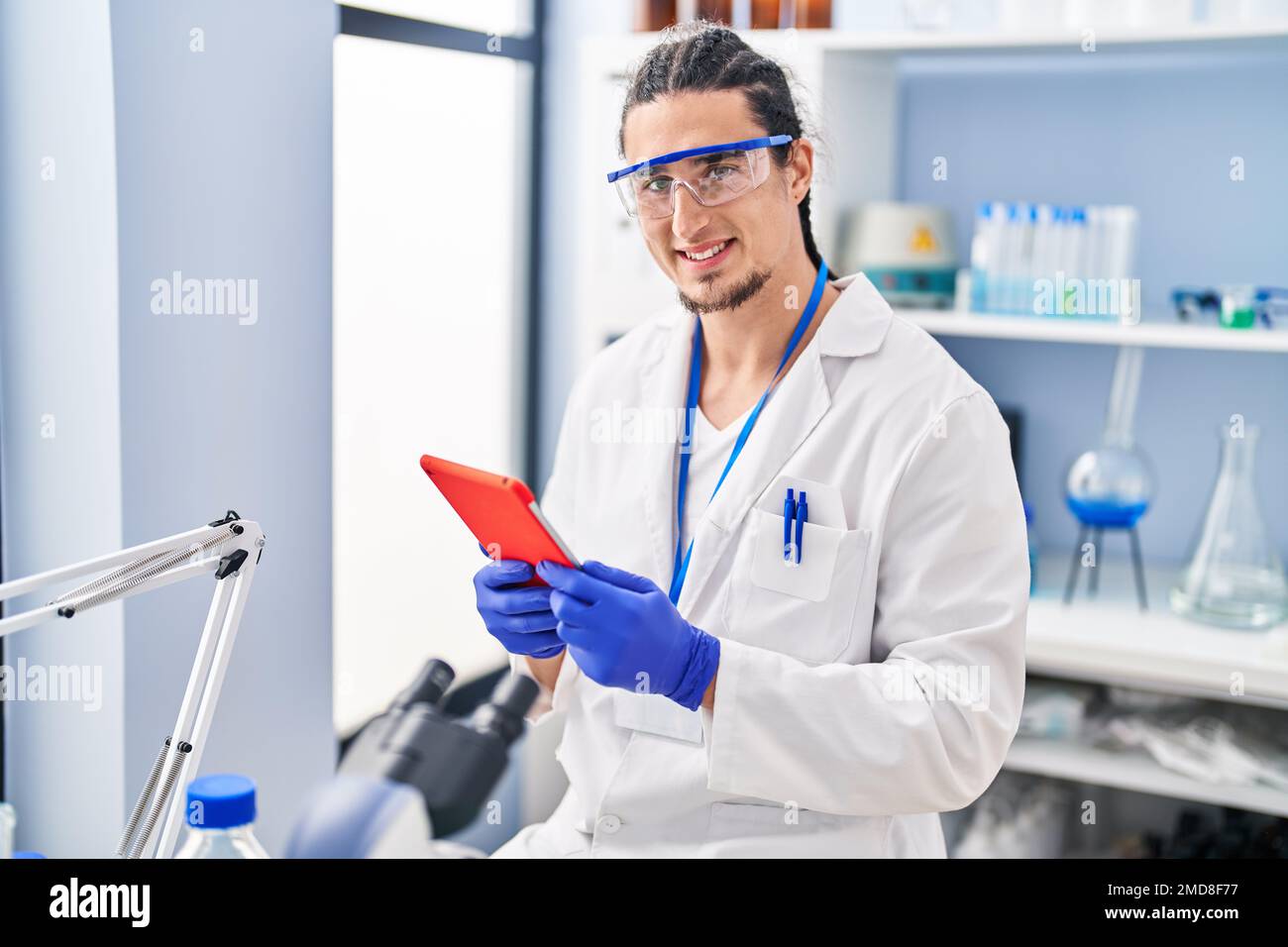 Young man wearing scientist uniform using touchpad at laboratory Stock Photo - Alamy