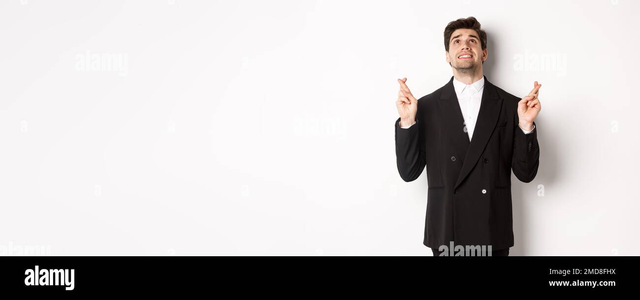 Portrait of tensed and worried handsome businessman, crossing fingers ...