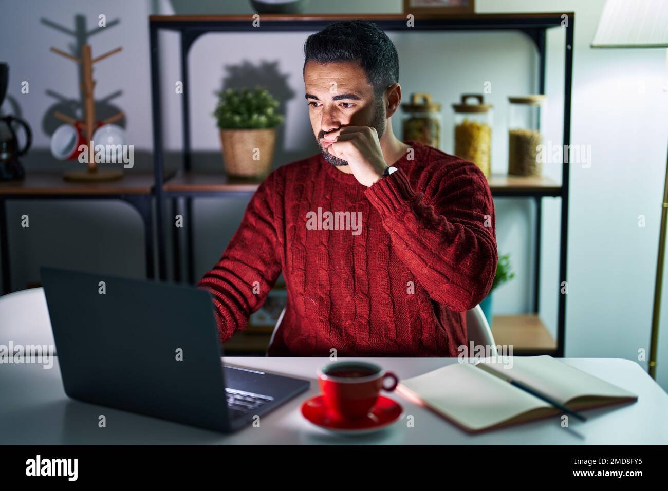 Young hispanic man with beard using computer laptop at night at home ...