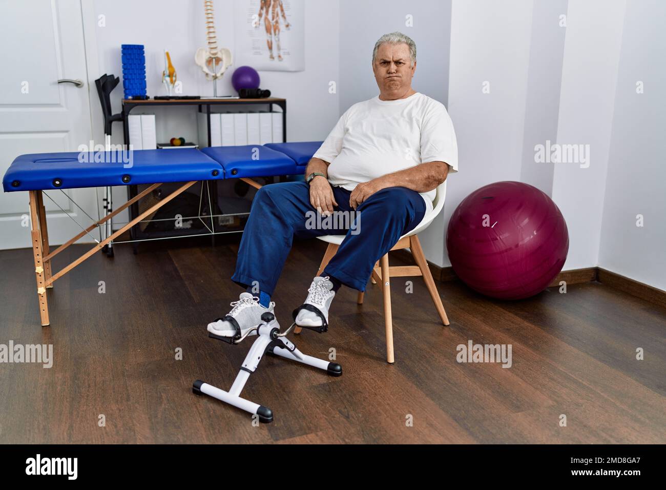 Senior caucasian man at physiotherapy clinic using pedal exerciser ...