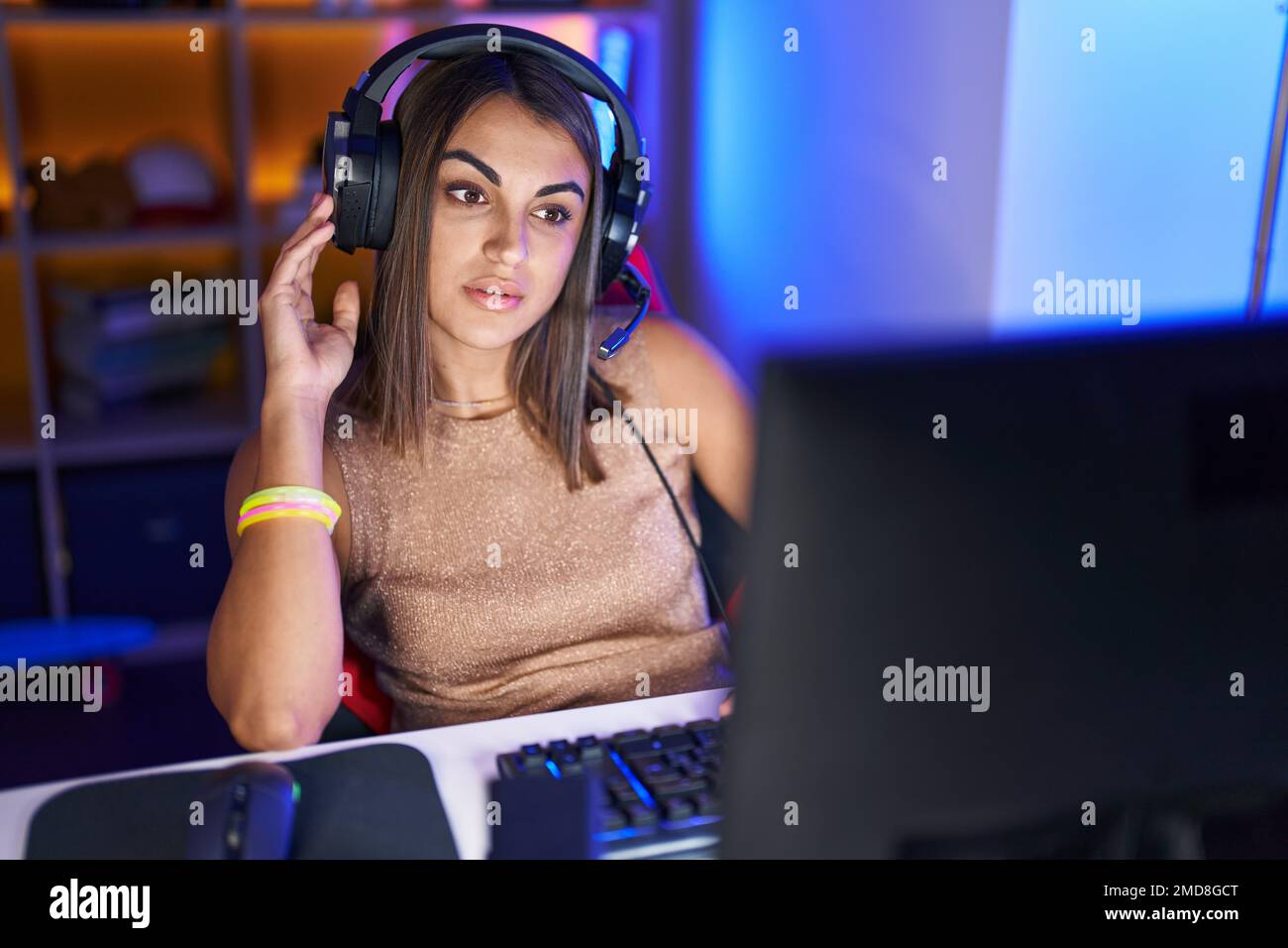 Young beautiful hispanic woman streamer playing video game using ...