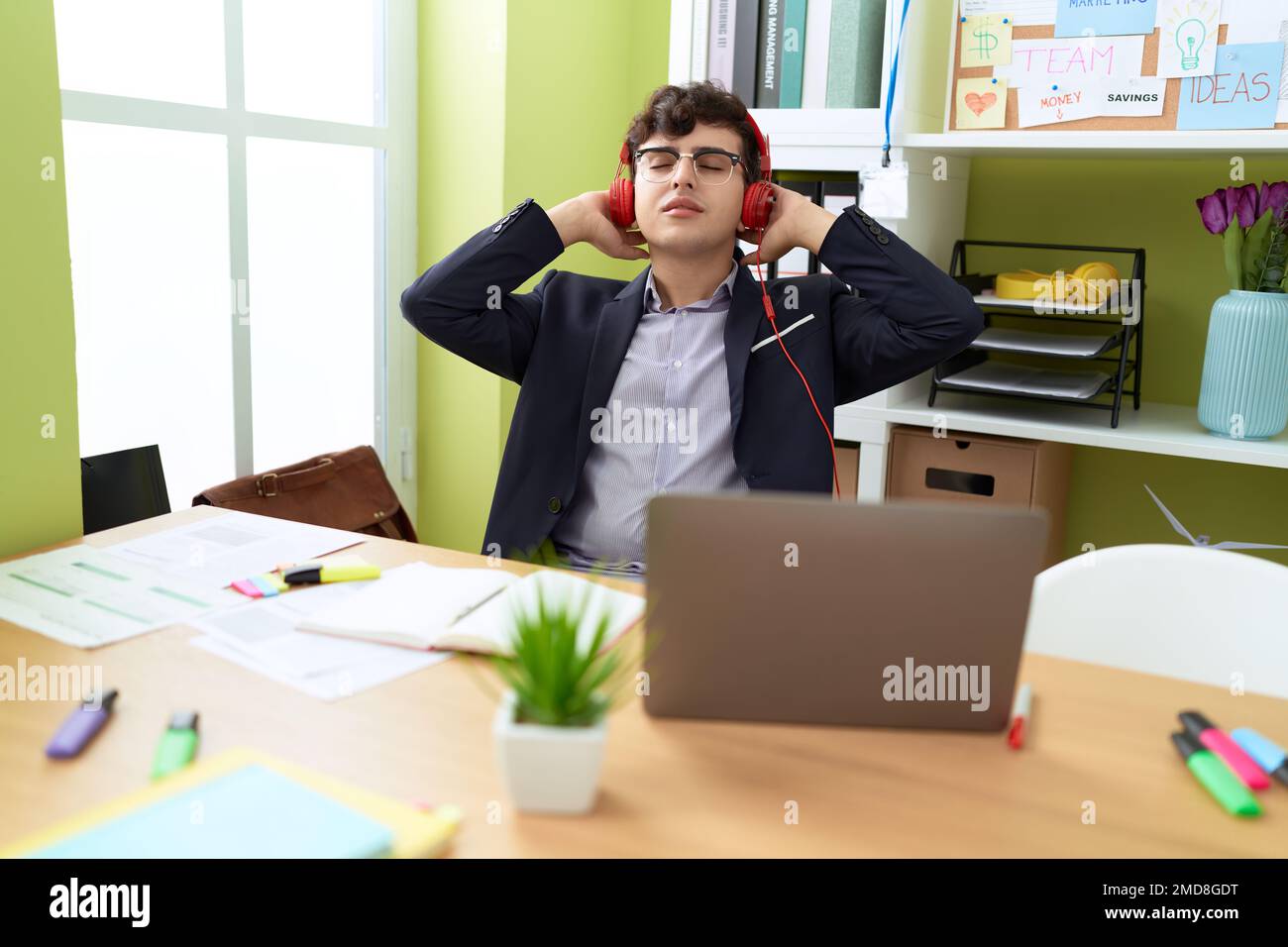 Non binary man business worker listening to music relaxed at office ...